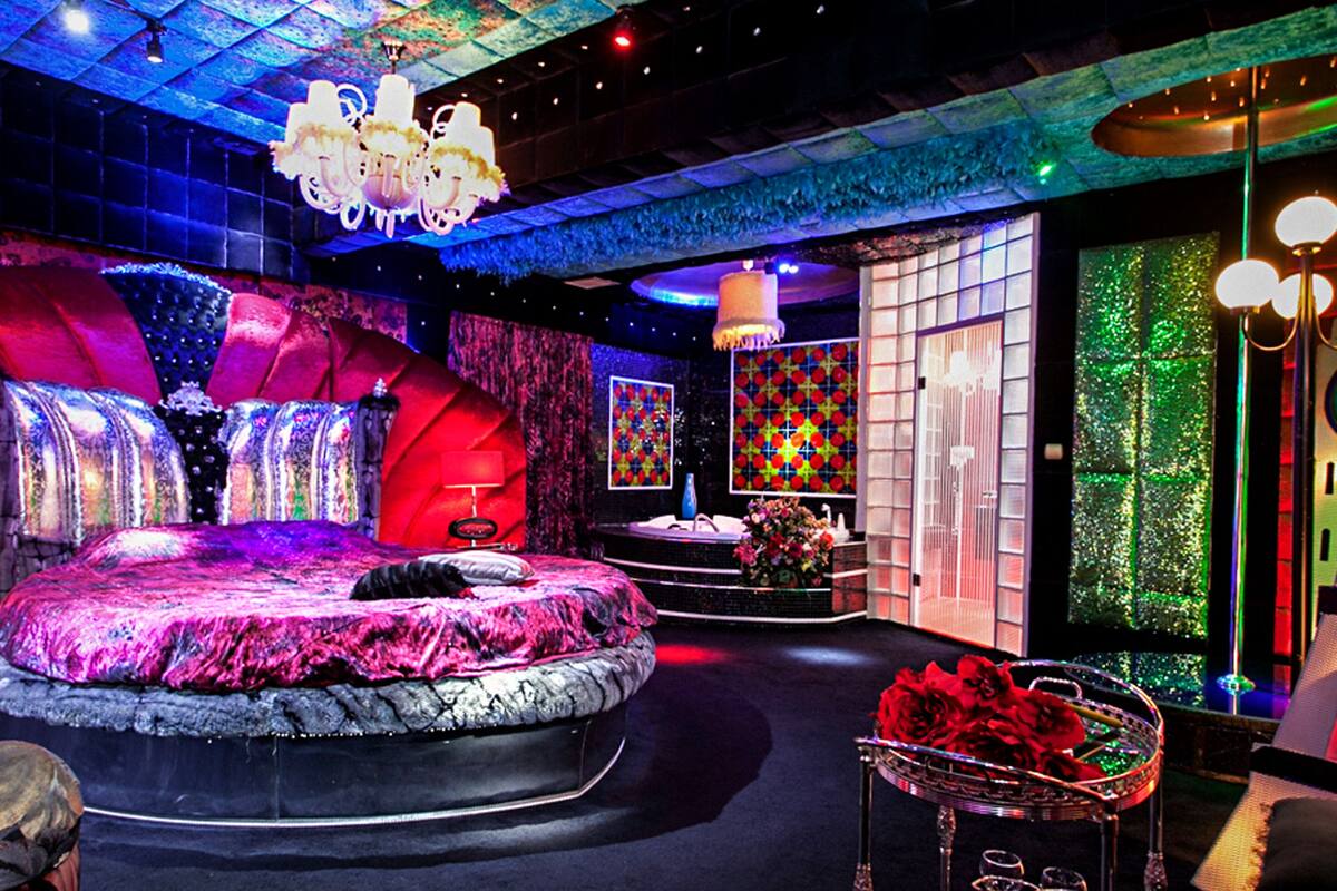 Um quarto luxuoso com uma cama grande, um lustre e uma parede decorativa.