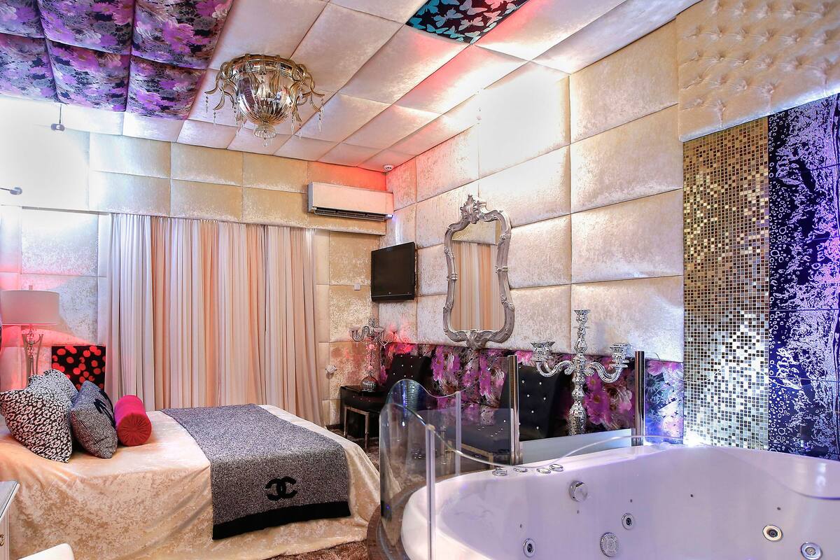 Um quarto luxuoso com uma cama grande, uma toucador com espelho, um candelabro e uma banheira.