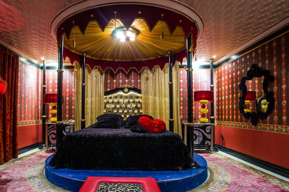 Um quarto luxuoso com uma cama grande, cortinas elaboradas e um candelabro.