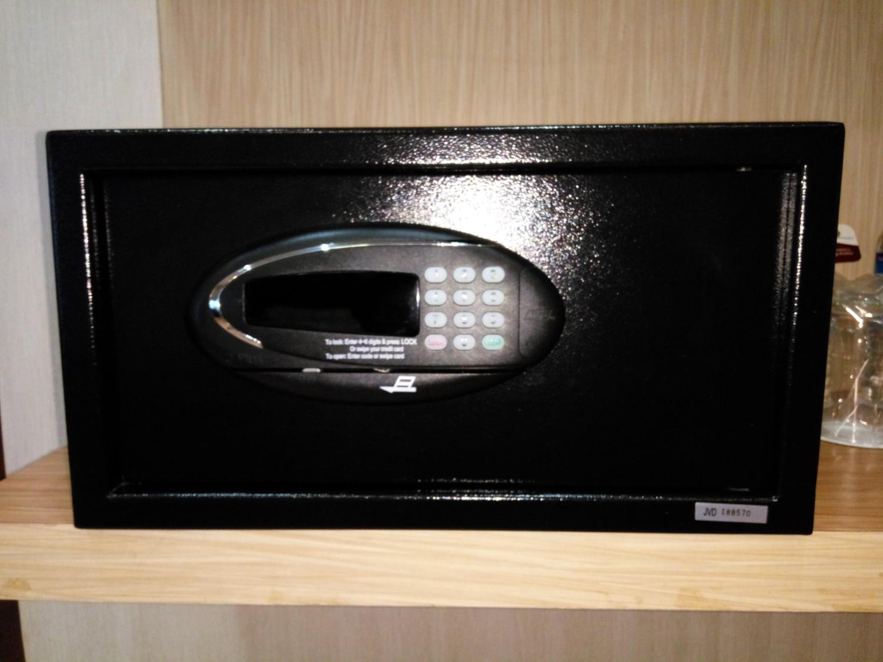 Forno de micro-ondas preto com painel de teclas e visor digital, sobre uma prateleira de madeira.