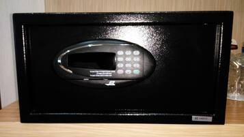 Forno de micro-ondas preto com painel de teclas e visor digital, sobre uma prateleira de madeira.