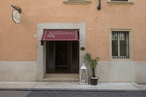 Fachada de edifício com toldo cor de vinho exibindo o nome 'Albergo Mazzanti'.