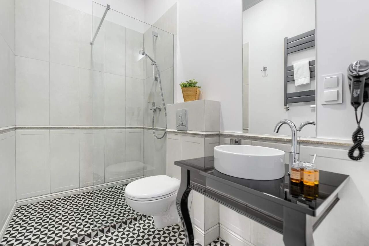 Uma casa de banho moderna com chuveiro, sanita e lavatório.