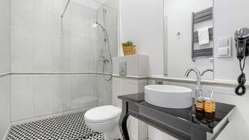 Uma casa de banho moderna com chuveiro, sanita e lavatório.