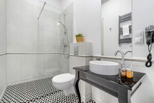 Uma casa de banho moderna com chuveiro, sanita e lavatório.
