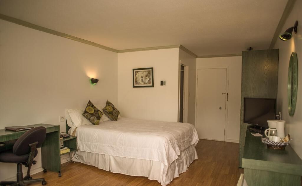 Quarto com cama, escrivaninha, cadeira e cómoda com espelho.