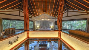Um quarto espaçoso com pé direito alto, uma cama com dossel e um espaço de estar com vista para o exterior.