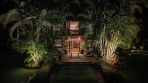 Um resort tropical com um edifício central, rodeado por vegetação exuberante e palmeiras.