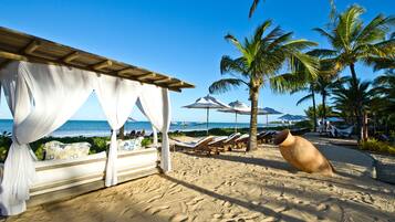 Na praia, espreguiçadeiras, guarda-sóis de praia, toalhas de praia