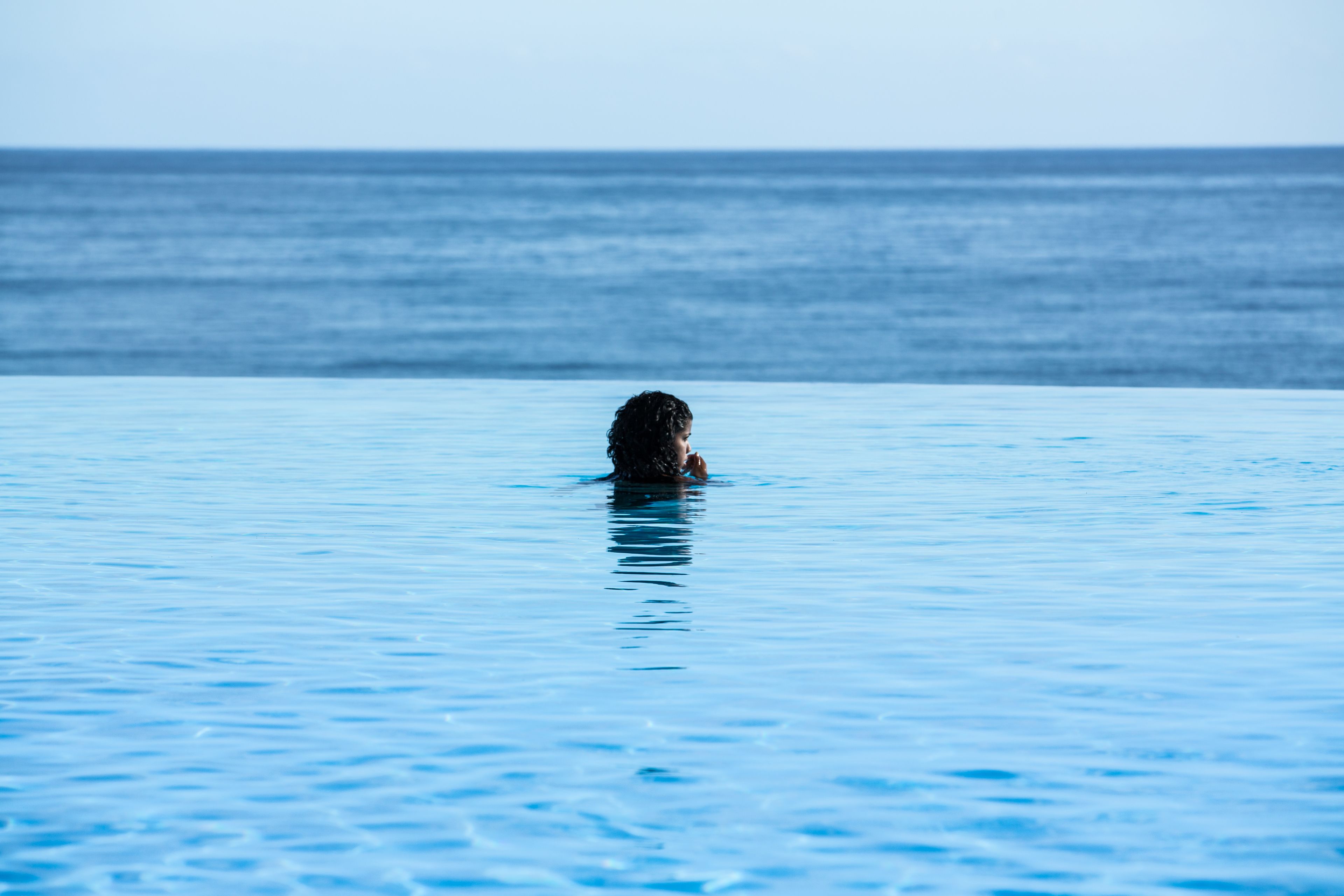 Uma pessoa em uma piscina com vista para o oceano.