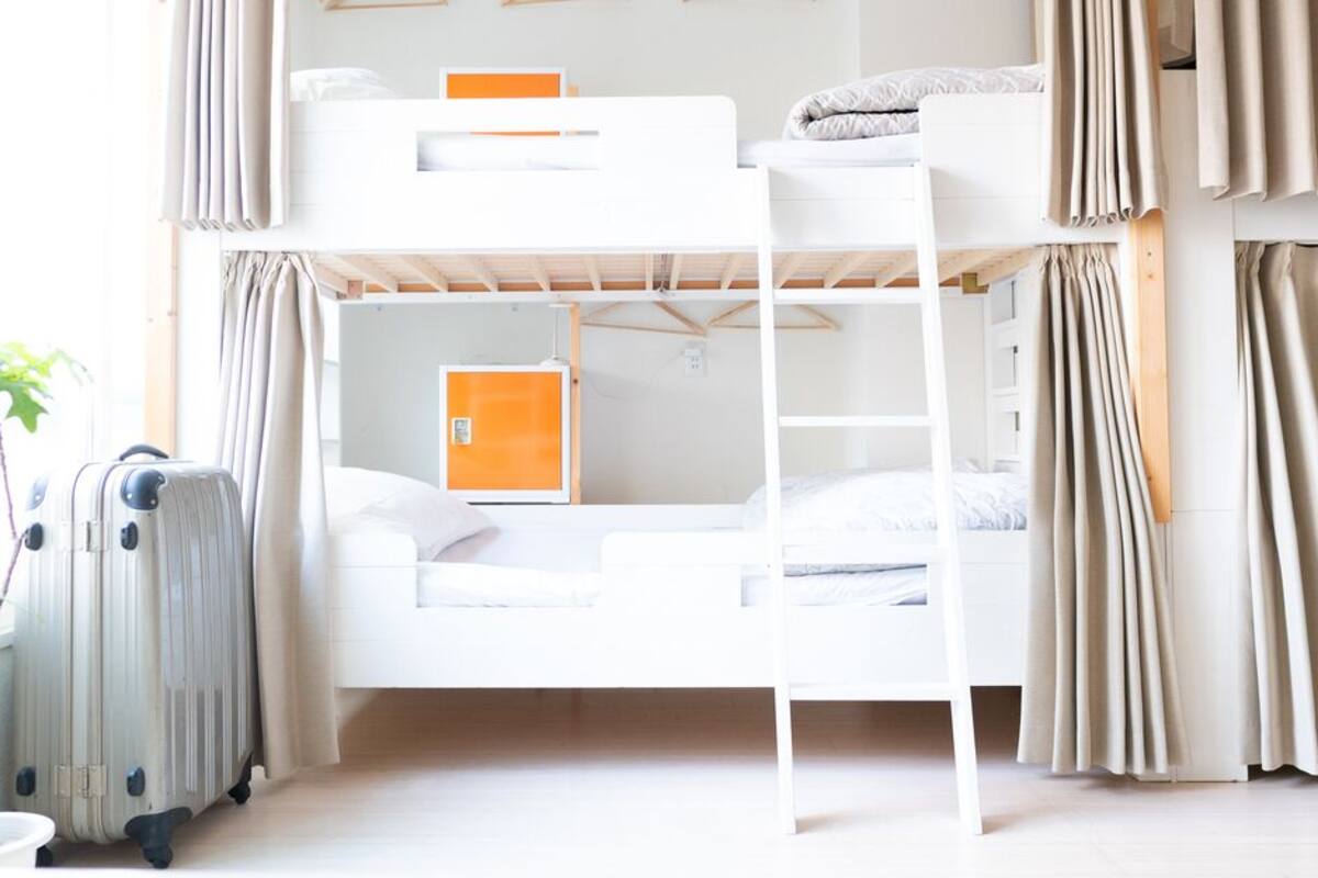Quarto com beliche, mala, radiador e cortinas.