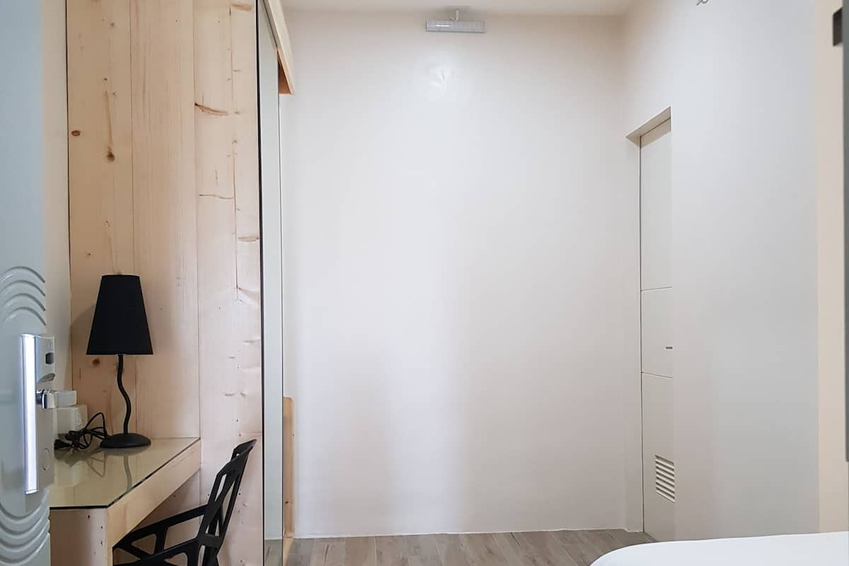 Quarto com uma cama, uma escrivaninha com cadeira e um guarda-roupa.