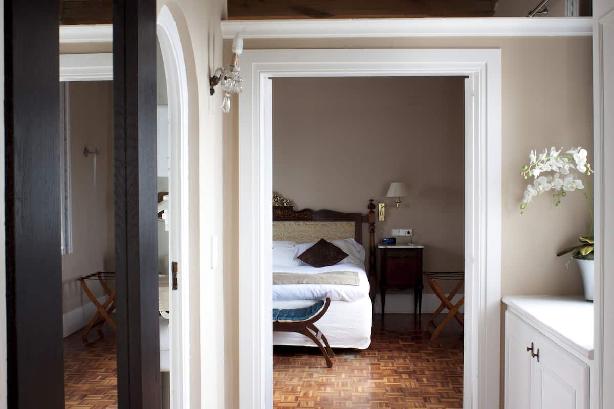 Quarto com cama, mesa de cabeceira, abajur e uma planta em vaso.
