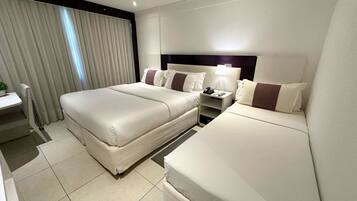Quarto de hotel com uma cama grande, mesas de cabeceira e um criado-mudo.