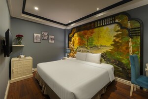 Quarto com cama grande, mesa de cabeceira, televisão e um mural na parede.