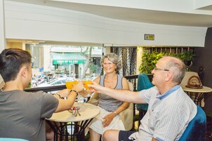 Um grupo de pessoas sentadas em uma mesa ao ar livre, brindando com bebidas.