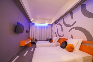 Quarto de hotel moderno com duas camas, televisão de tela plana, escrivaninha e uma janela grande com cortinas.