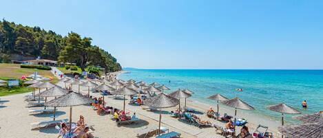 Na praia, praia de areia branca, espreguiçadeiras, guarda-sóis de praia