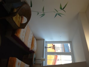 Quarto com cama, janela e planta pendurada.