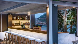 Uma área de bar com um balcão comprido, vários bancos e uma variedade de garrafas.