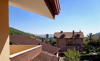 Um edifício residencial com telhado telhado, varanda e vista para uma paisagem montanhosa.