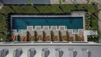Vista aérea de uma área de piscina no terraço, com piscina retangular, espreguiçadeiras e um espaço de estar coberto.