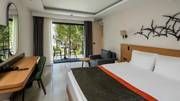 Quarto de hotel com cama, escrivaninha, cadeira, mesa pequena e varanda com área de estar externa.