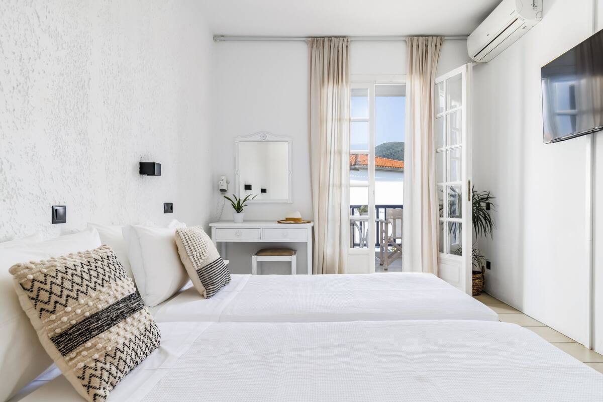 Quarto de hotel moderno com uma cama grande, uma escrivaninha, um espelho e uma televisão.
