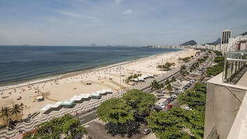 Uma praia com vista para o oceano e um horizonte urbano ao fundo.
