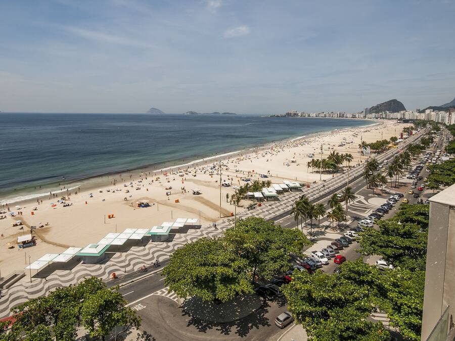 Uma praia com vista para o oceano e um horizonte urbano ao fundo.