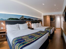Quarto de hotel com duas camas, um grande mural, mobiliário de madeira e um closet espaçoso.
