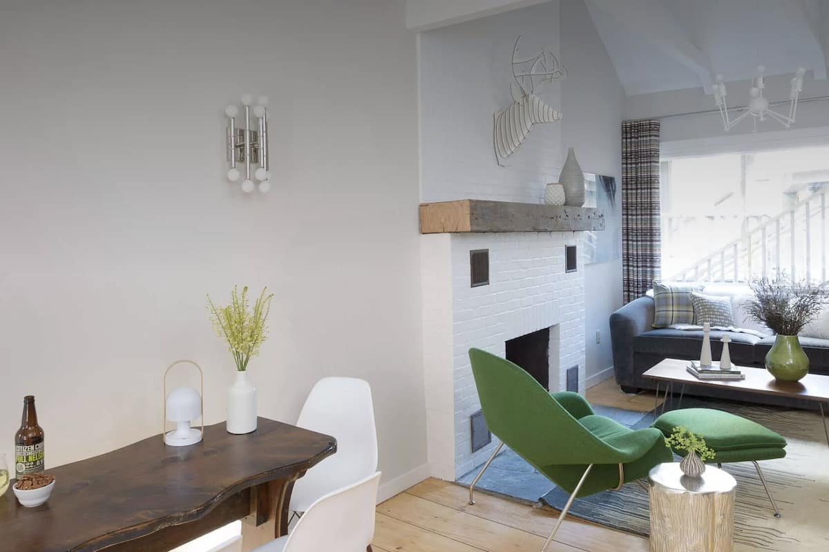 Uma sala de estar moderna com lareira, um sofá, uma mesa de jantar com cadeiras e uma mesa de centro.