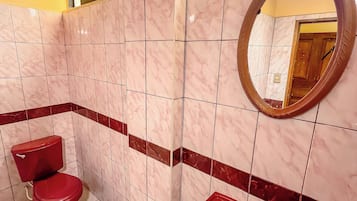 Um banheiro com vaso sanitário vermelho, pia vermelha e espelho na parede.