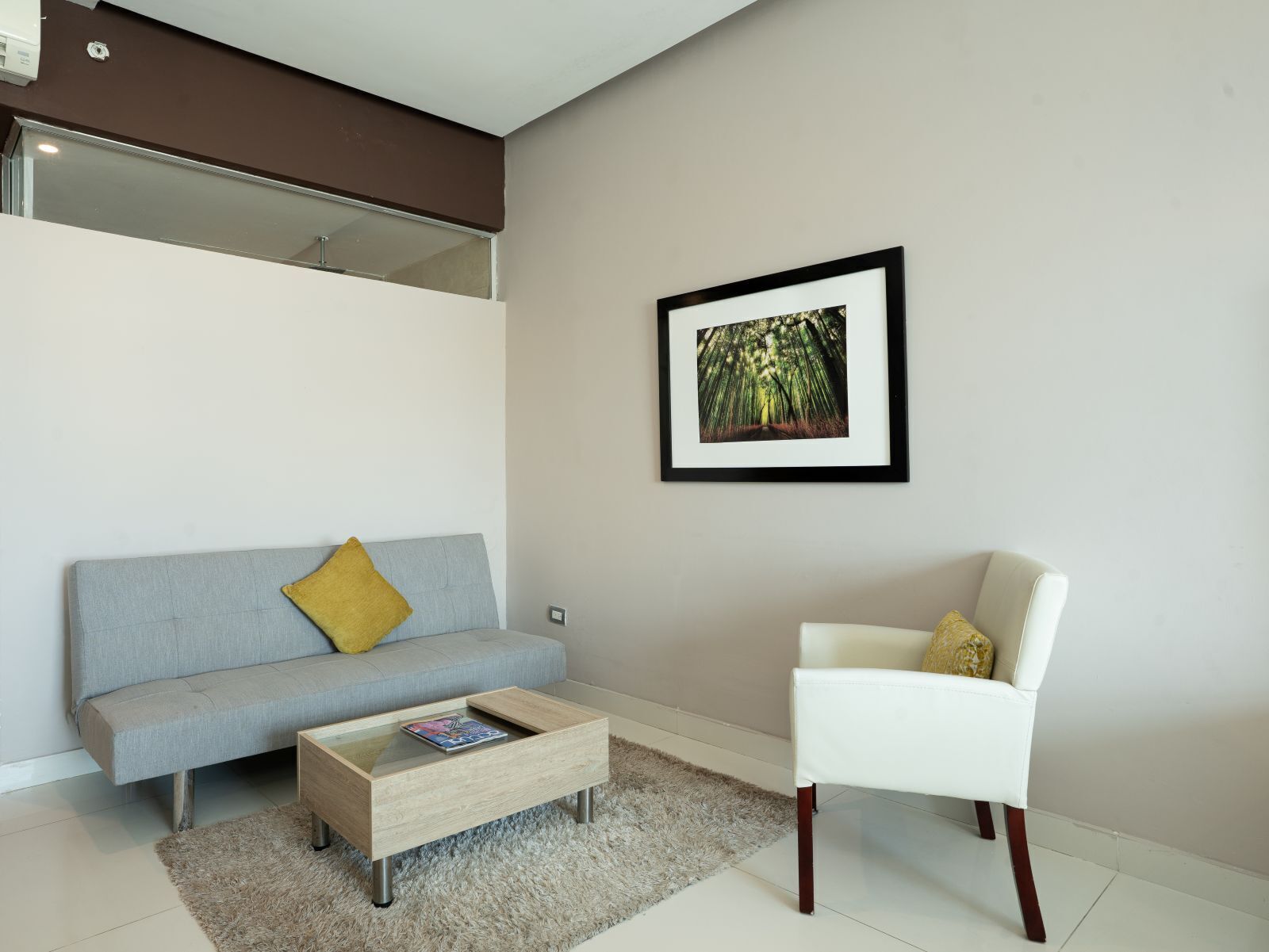 Uma sala de estar moderna com um sofá, uma mesa de centro, uma poltrona e um quadro na parede.