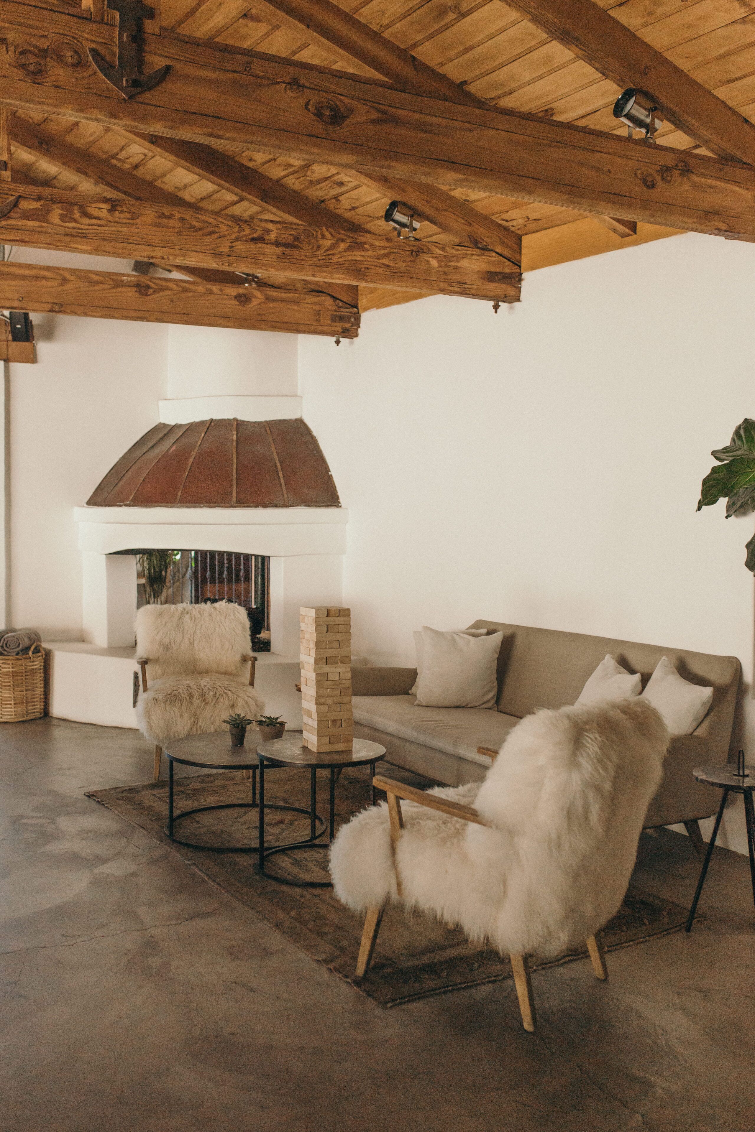 Um quarto espaçoso com teto alto, lareira, sofá e duas poltronas.