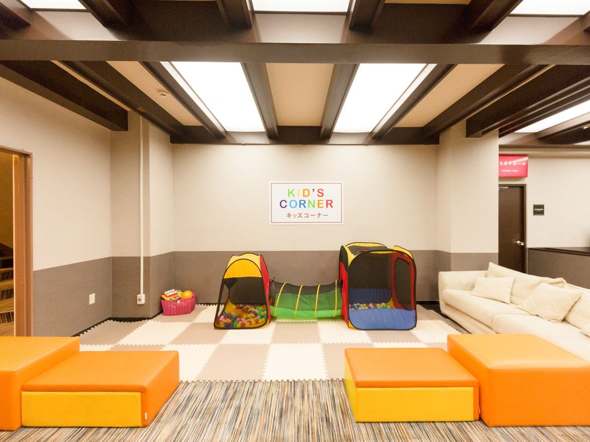 Uma área de recreação infantil com duas tendas de brincar e uma mesinha com brinquedos.