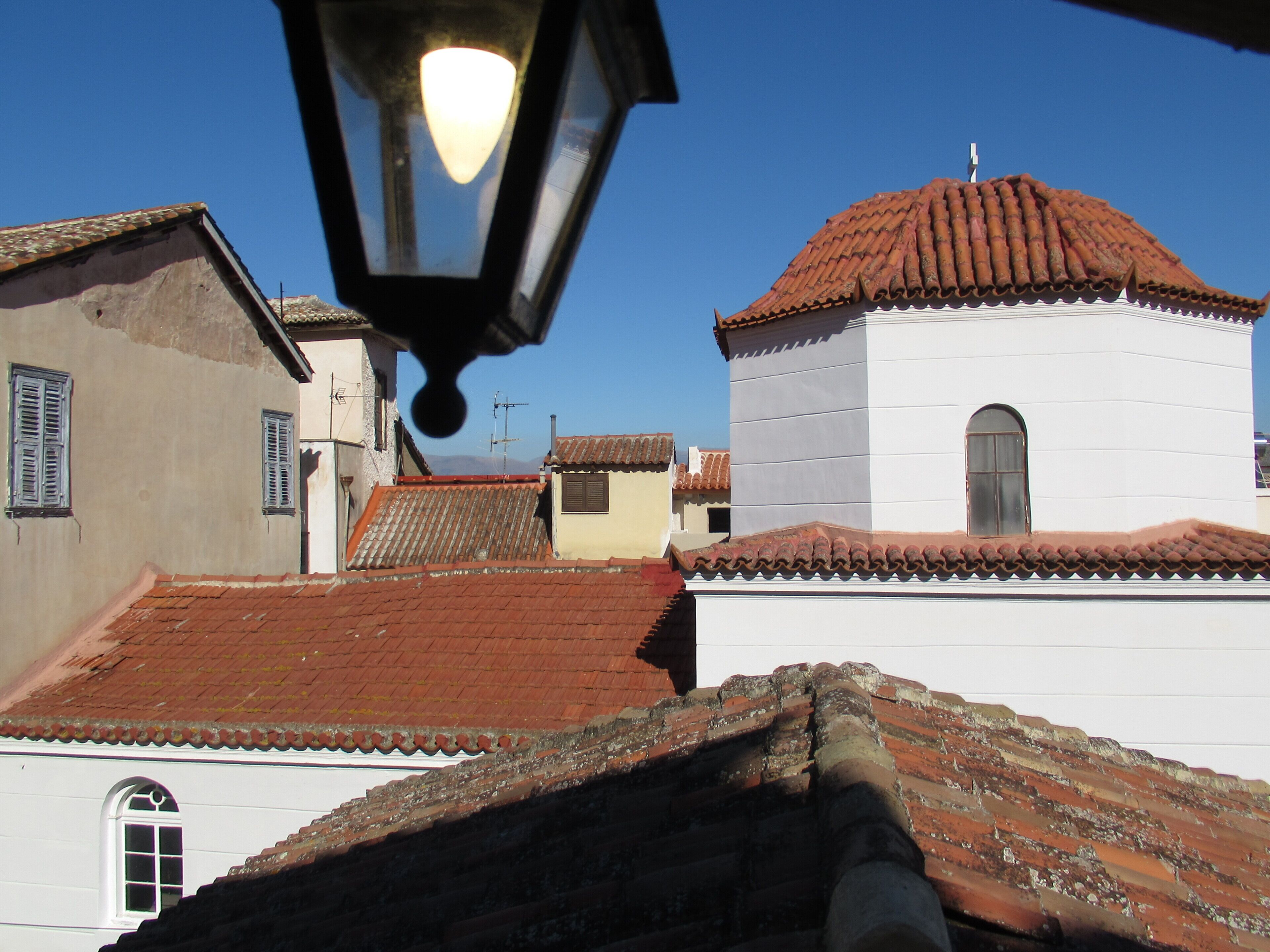 Um edifício tradicional com telhado de telhas vermelhas, paredes brancas e uma pequena torre sineira.