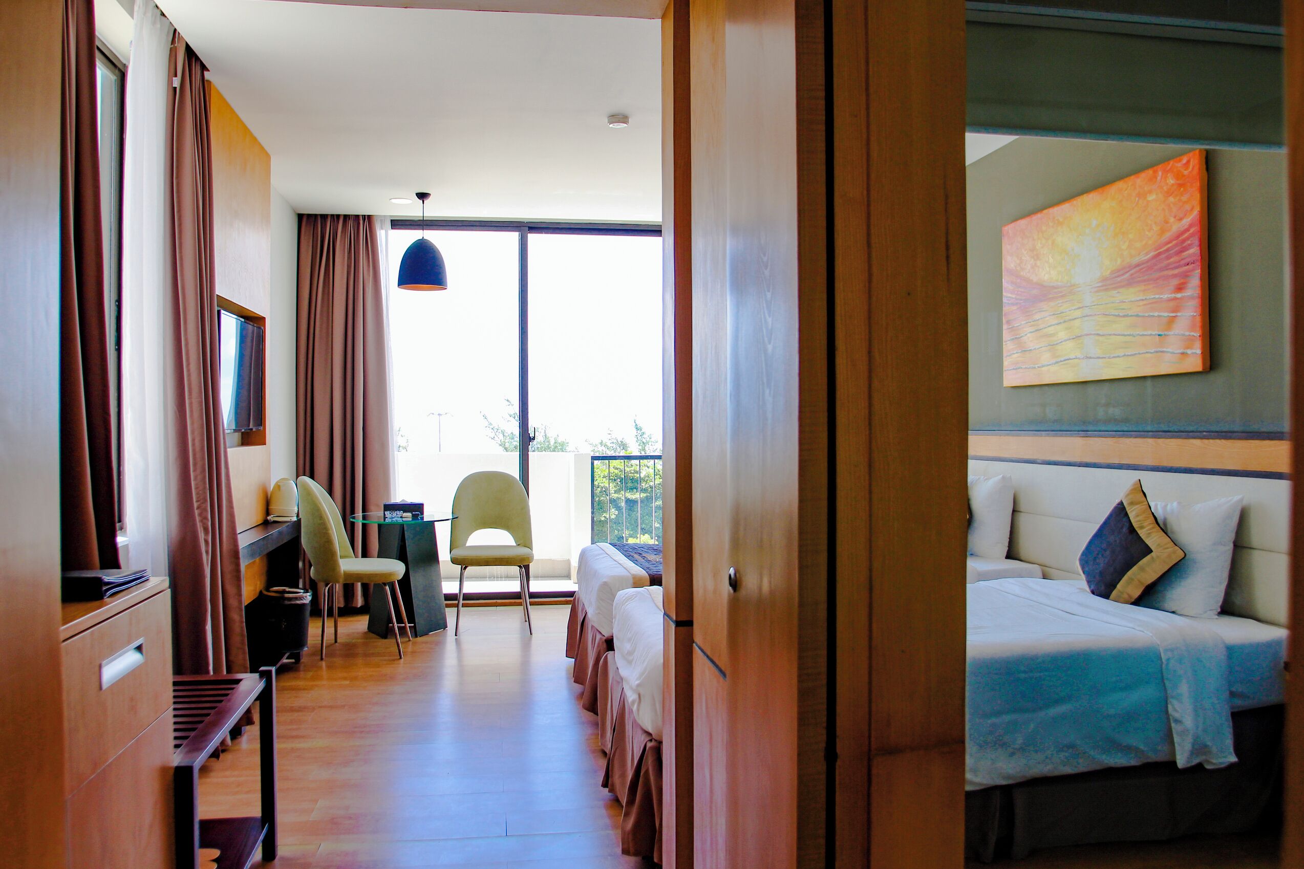 Quarto de hotel com cama, escrivaninha, cadeira e vista para o exterior.