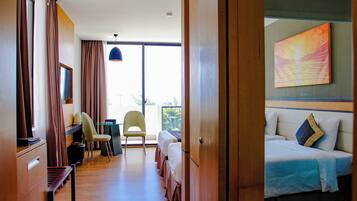 Quarto de hotel com cama, escrivaninha, cadeira e vista para o exterior.