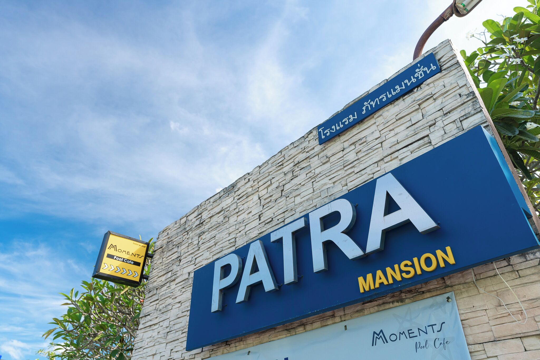 Placa indicando 'Patra Mansion' com sinalização para o café junto à piscina.