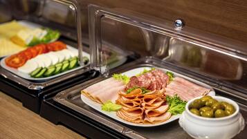 Buffet com diversos alimentos, incluindo carnes fatiadas, queijos e legumes.