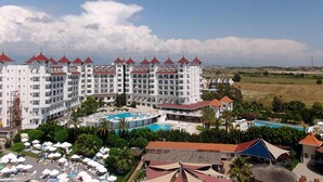 Um hotel com vários edifícios brancos, telhados vermelhos e uma grande área de piscina central.