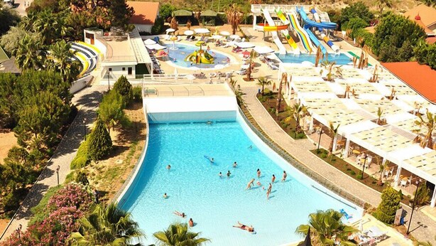 Um resort com uma grande piscina, toboáguas e espreguiçadeiras.