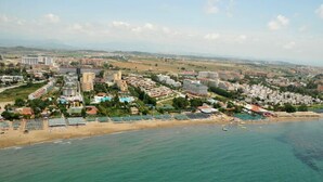 Vista aérea de um resort à beira-mar com vários edifícios, uma praia e uma visão clara do oceano.