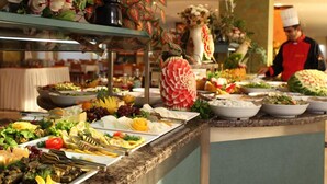 Buffet com diversos alimentos e plantas decorativas.