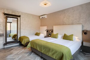 Quarto de hotel com duas camas, um espelho grande, um lustre e um ar condicionado fixado na parede.