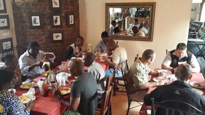 Um grupo de pessoas jantando em um restaurante com parede de tijolos e quadros emoldurados.