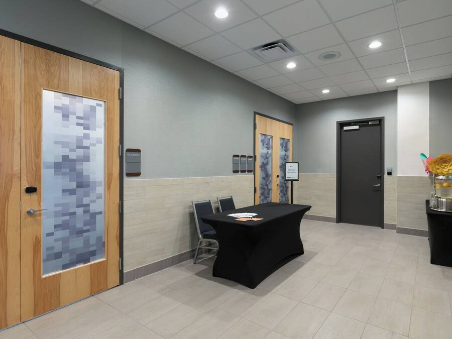 Uma sala de conferências com uma mesa preta, cadeiras e uma porta com um design pixelizado.
