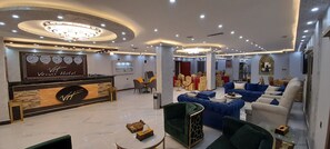 Um hall de hotel com balcão de recepção, área de estar e um candelabro.