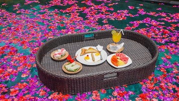 Uma bandeja de vime com comida e bebida sobre uma superfície coberta de flores.